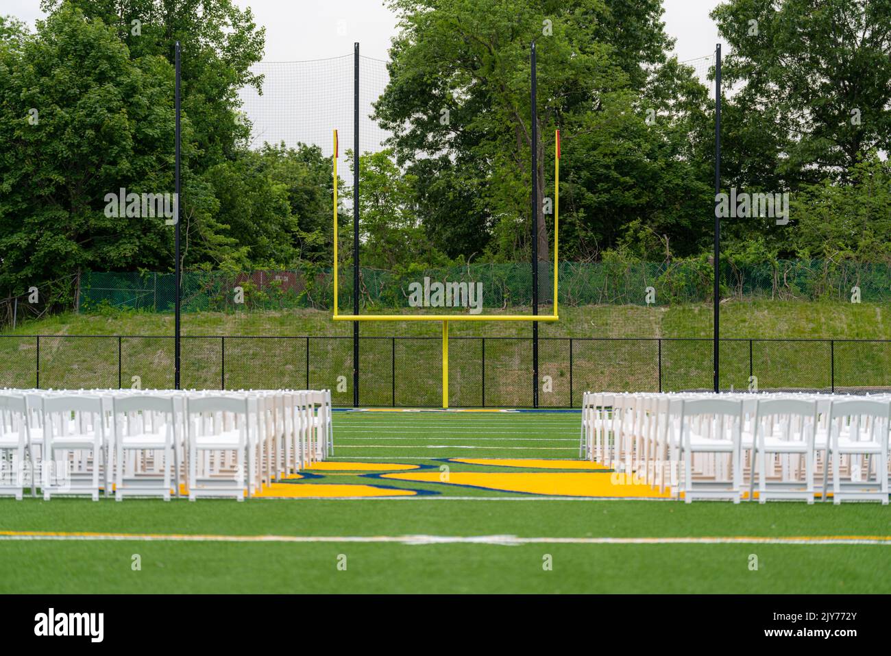 White chairs set-up in rows on a green synthetic turf athletic field ...