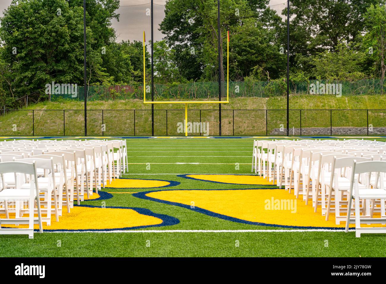 White chairs set-up in rows on a green synthetic turf athletic field ...