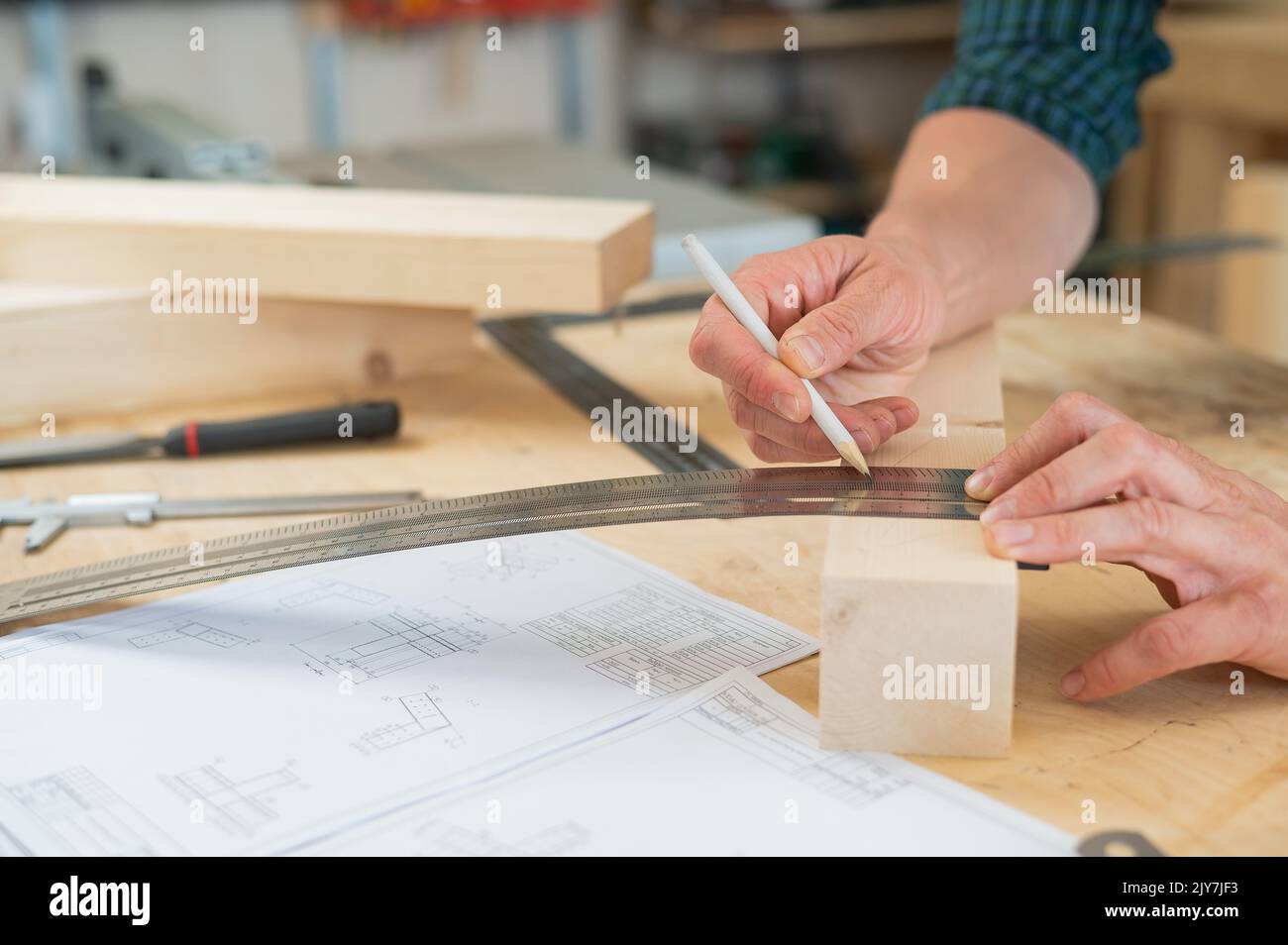 A carpenter measures wooden planks and makes marks with a pencil in a ...