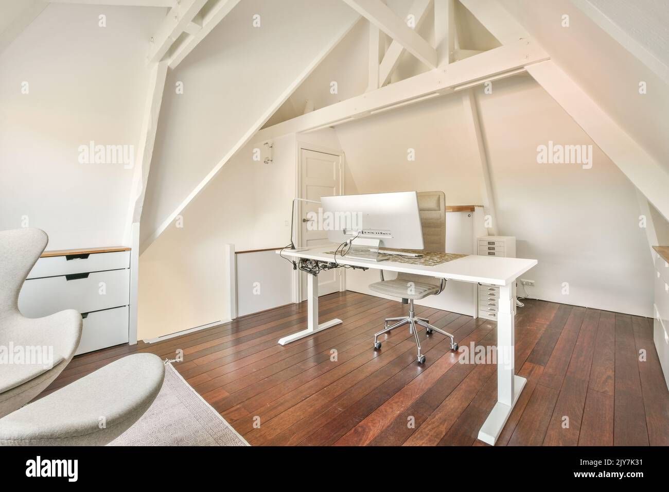 Comfortable chair placed near desk with computer monitors and ...