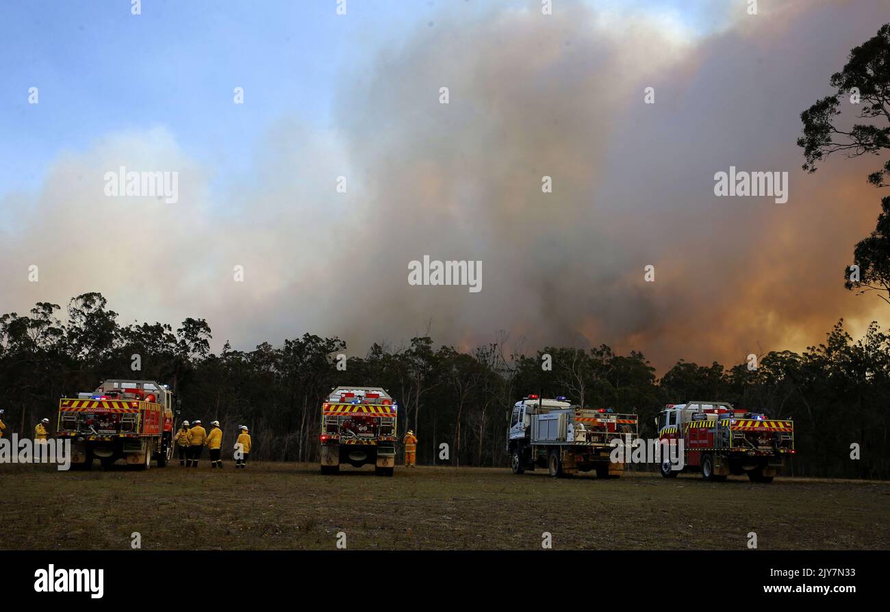 Firefighters watch a fire approach a property at Old Bar, Sunday ...