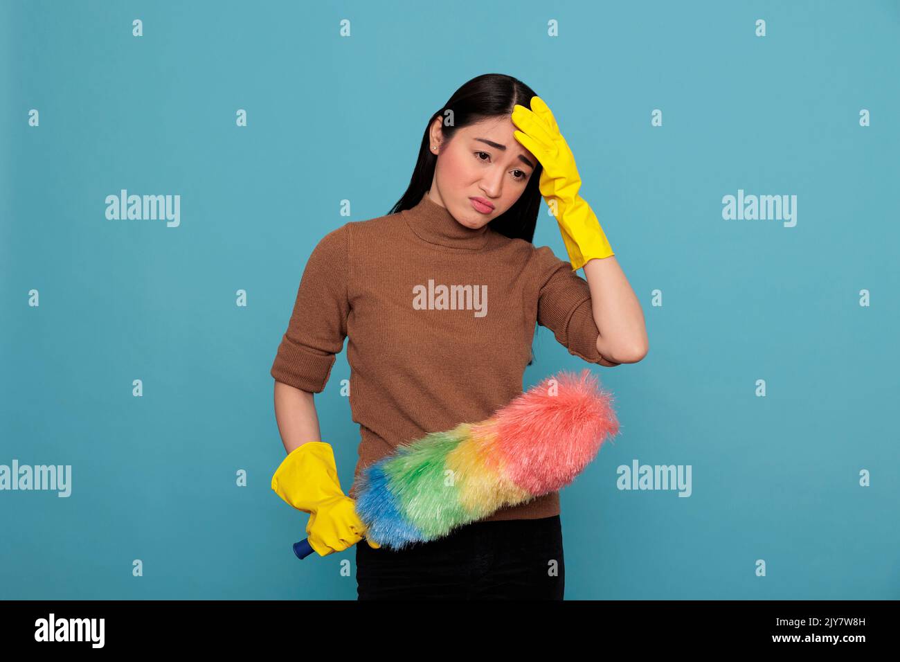 Sad depressed and overwhelmed asian housemaid tired from chores holding ...