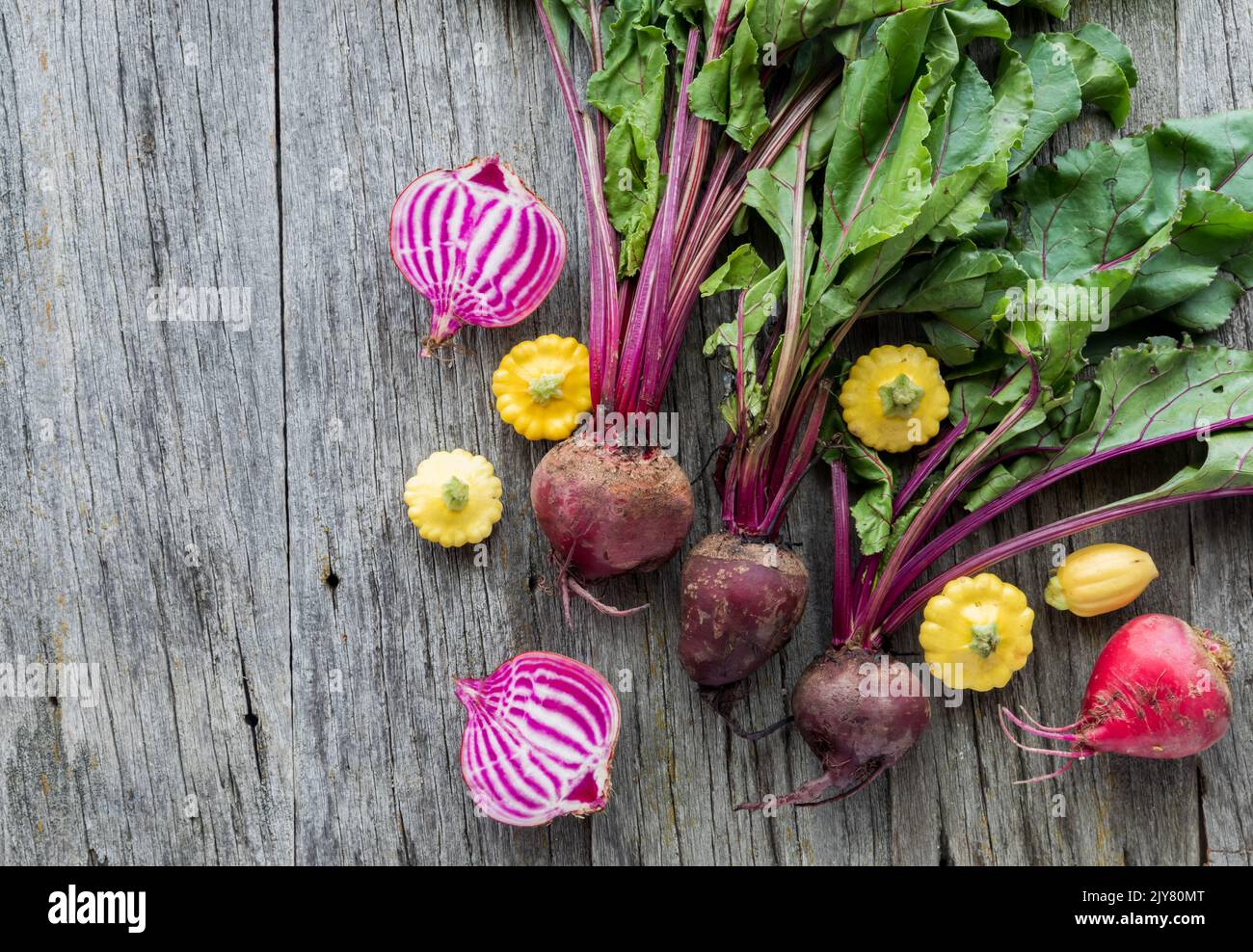 Fresh organic raw beets and patty pan squash on a rustic wooden table ...