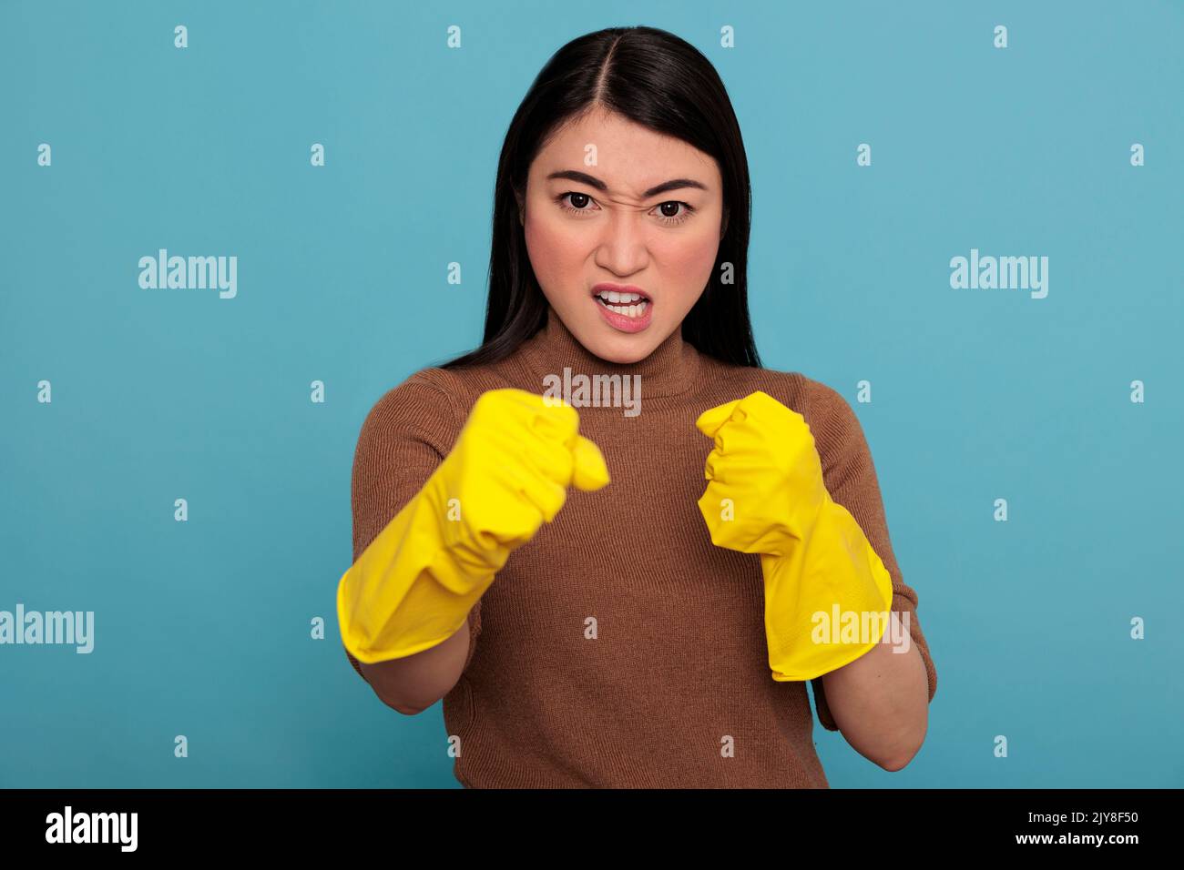 Angry aggressive asian housewife in standing in fight pose at chores ...