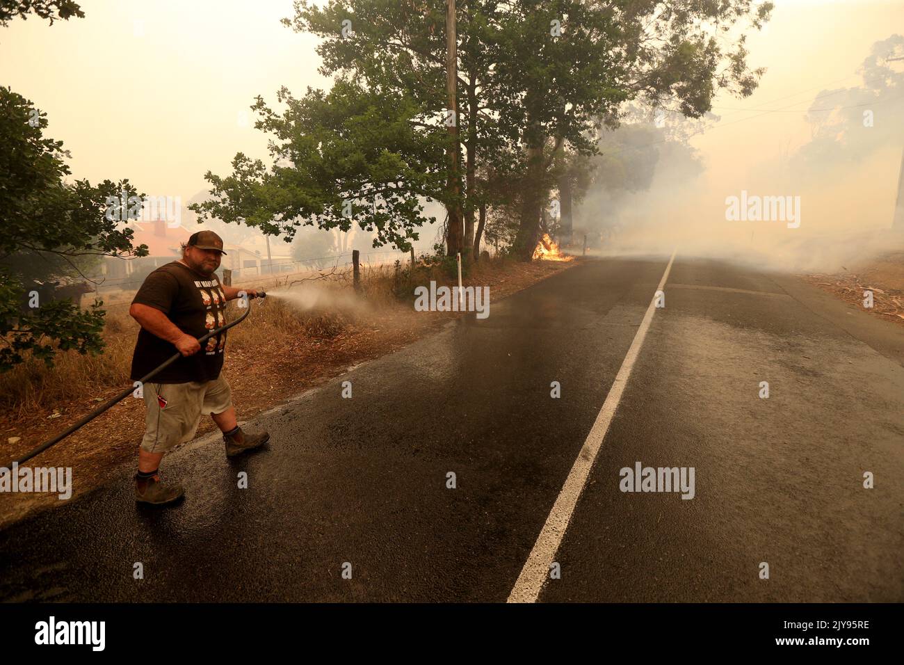 A Woodside resident battles a fire as it crosses Ridge Road at Woodside ...