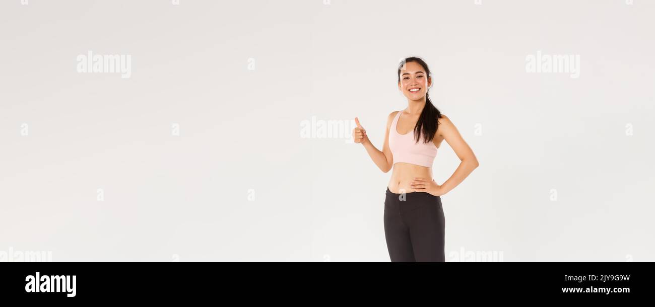 Full length of satisfied smiling, cute asian fitness girl, sportswoman ...