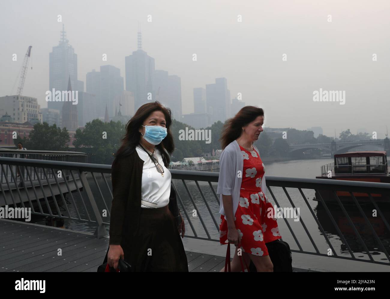 People wear breathing masks to protect themselves from a thick smoke ...