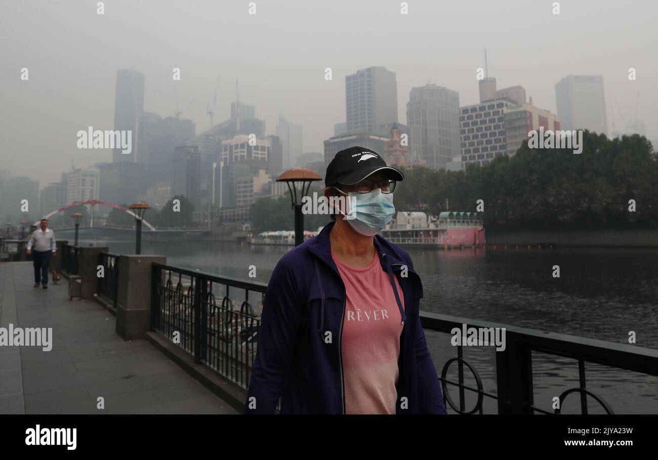 People wear breathing masks to protect themselves from a thick smoke ...