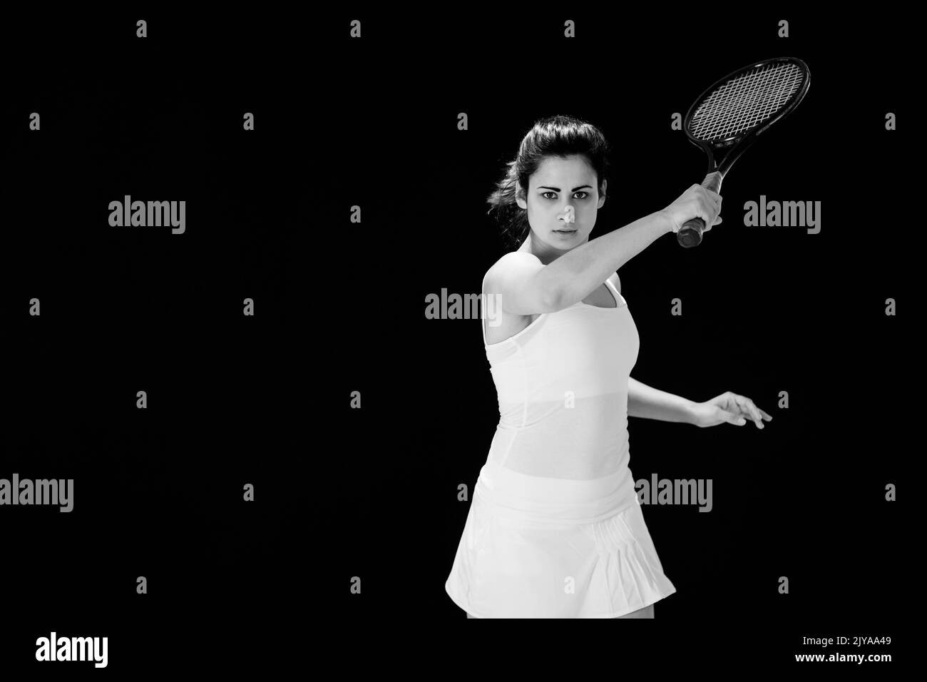 Confident young female sportsperson playing tennis against black ...