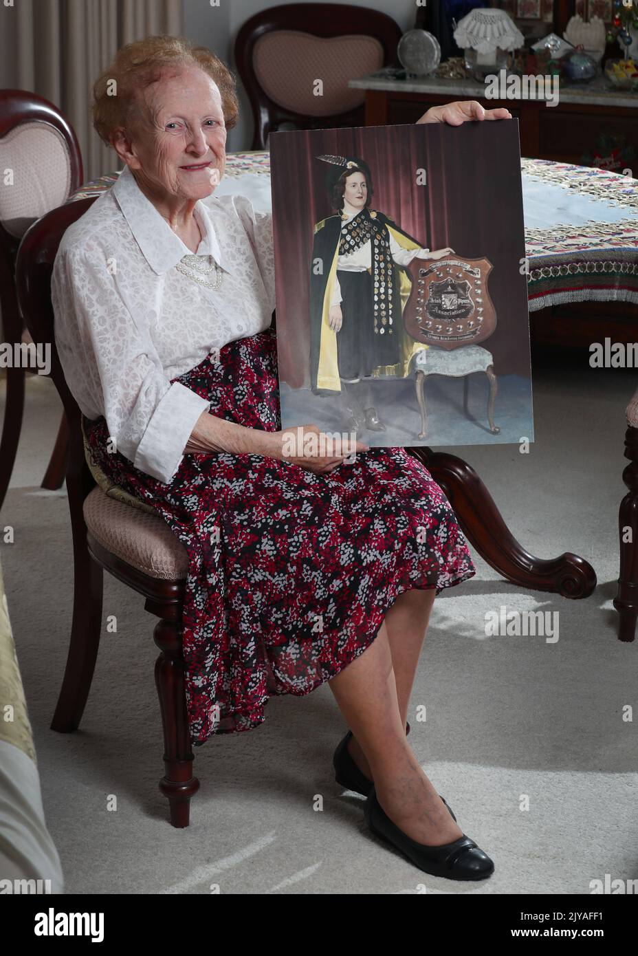 Geraldine Ryan, 89, poses for a photograph holding a portrait of ...