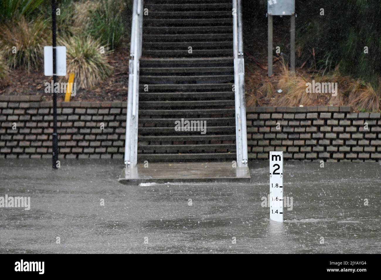 A flood gauge sign is seen as water overflows the banks of the ...