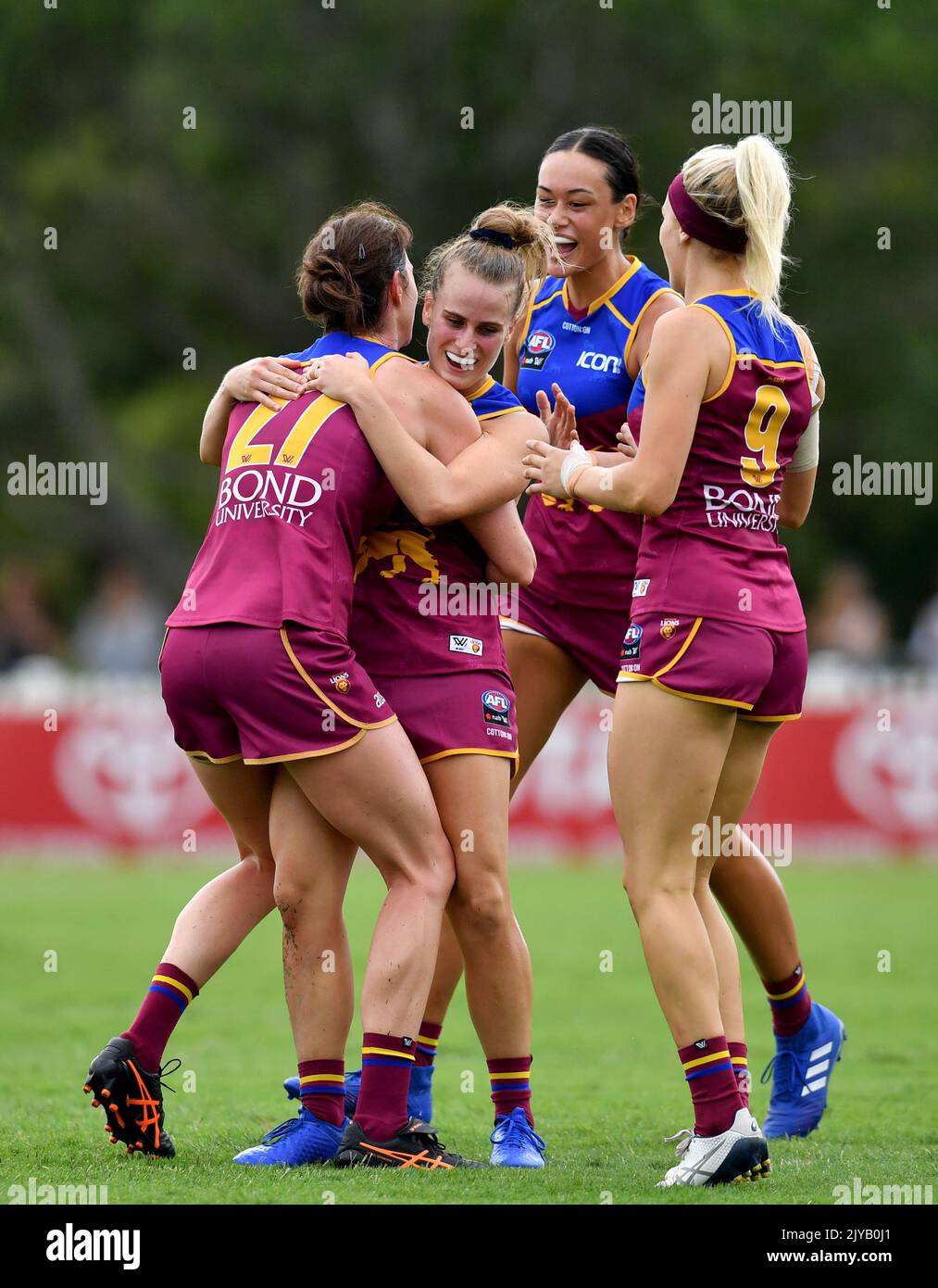 Greta Bodey (centre) of the Lions celebrates kicking a goal with team ...