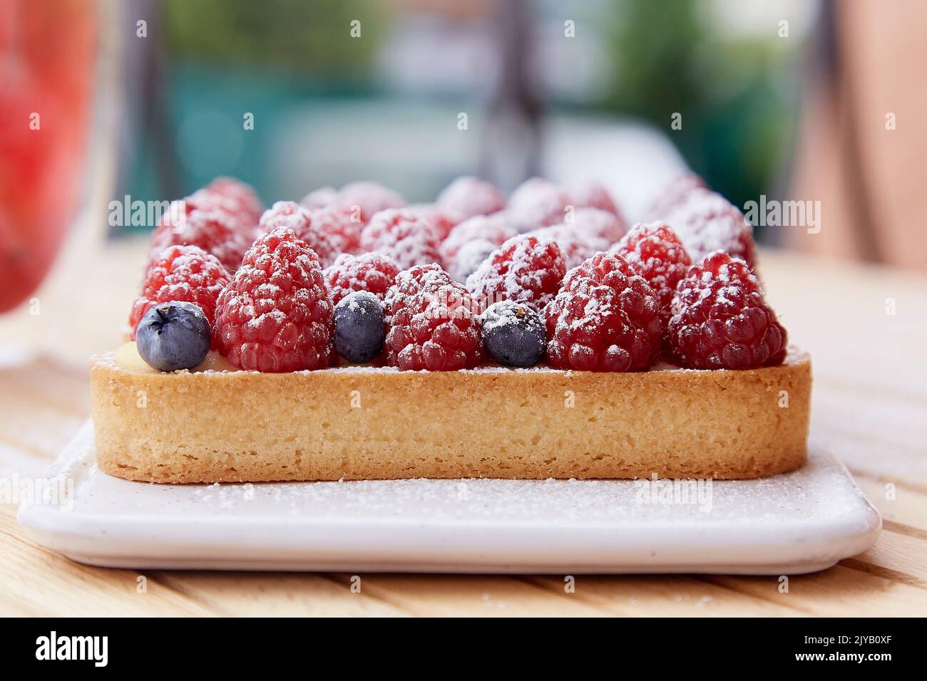 French blueberry and raspberry tart on white ceramic plate. Top view ...