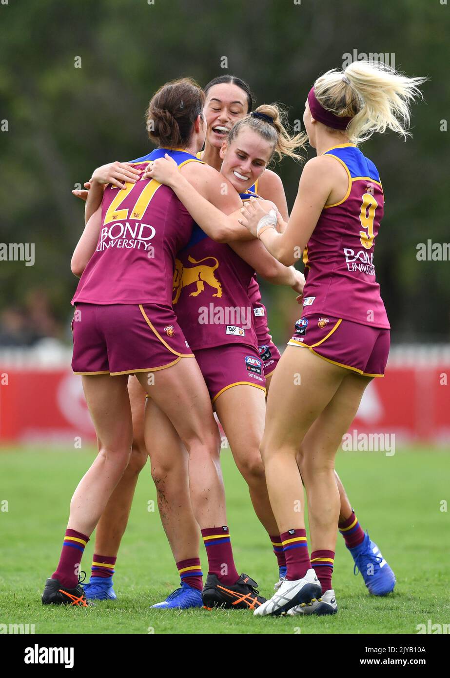 Greta Bodey (centre) of the Lions celebrates kicking a goal with team ...