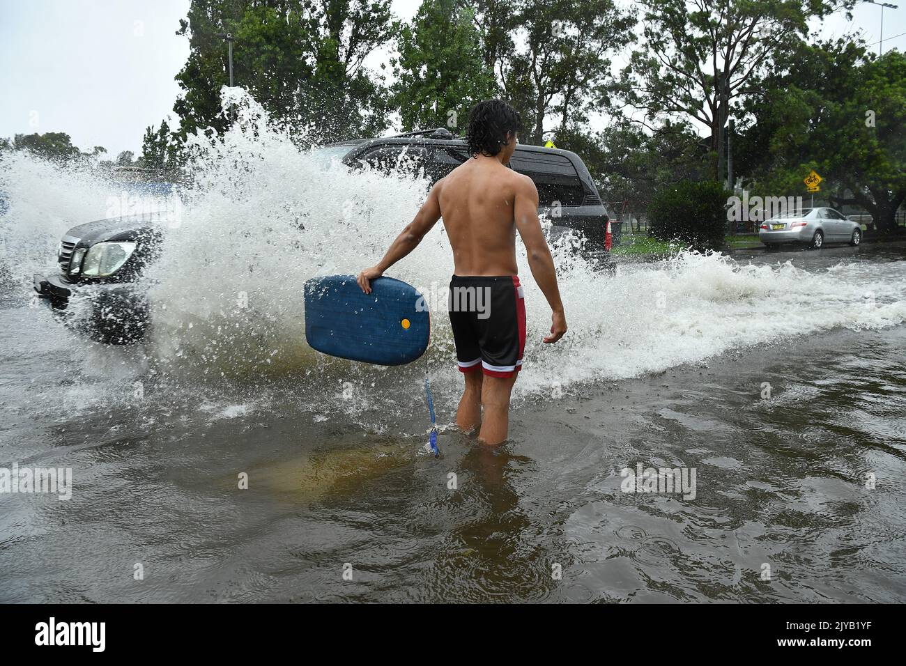 A group of boys direct traffic through floodwater at Tempe in Sydney ...