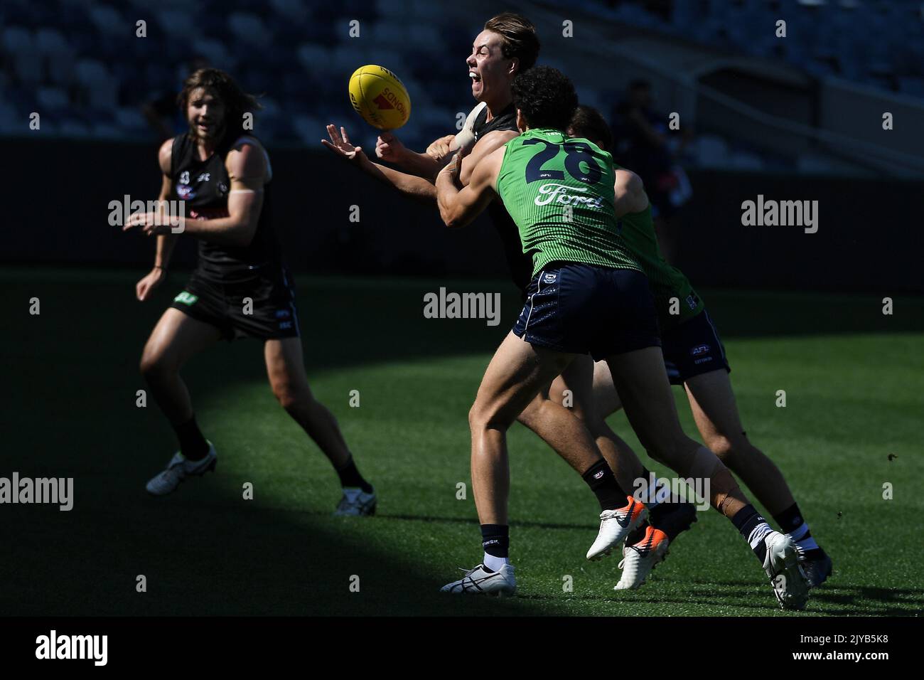 Tyler Brown (centre) of Collingwood gets a handball away under pressure ...