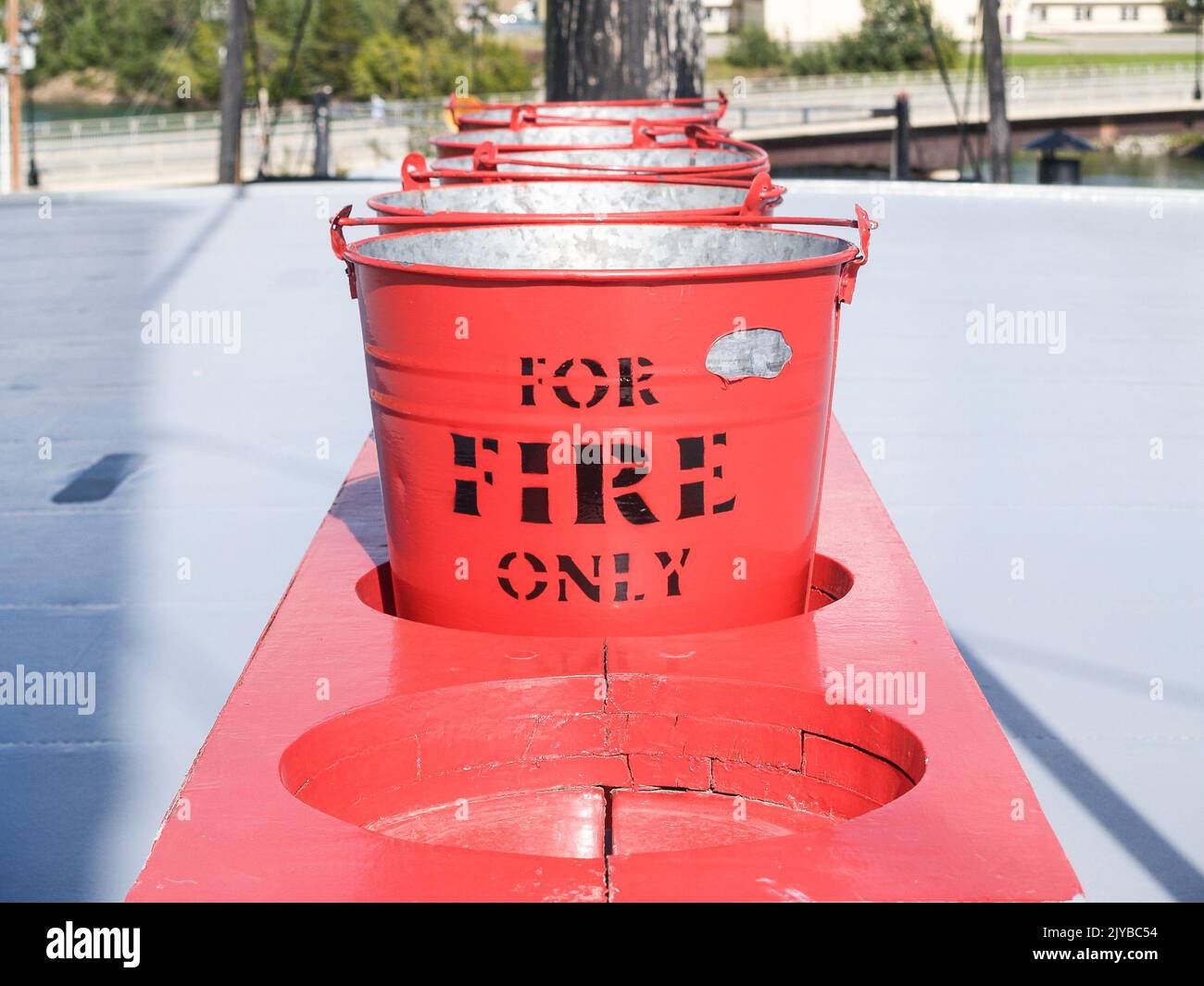 Row of red buckets in rack with sign for fire only for emergency Stock ...