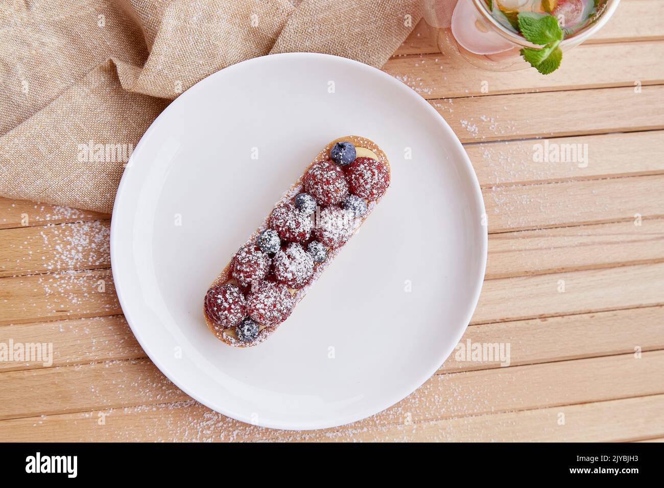 French blueberry and raspberry tart on white ceramic plate. Top view ...