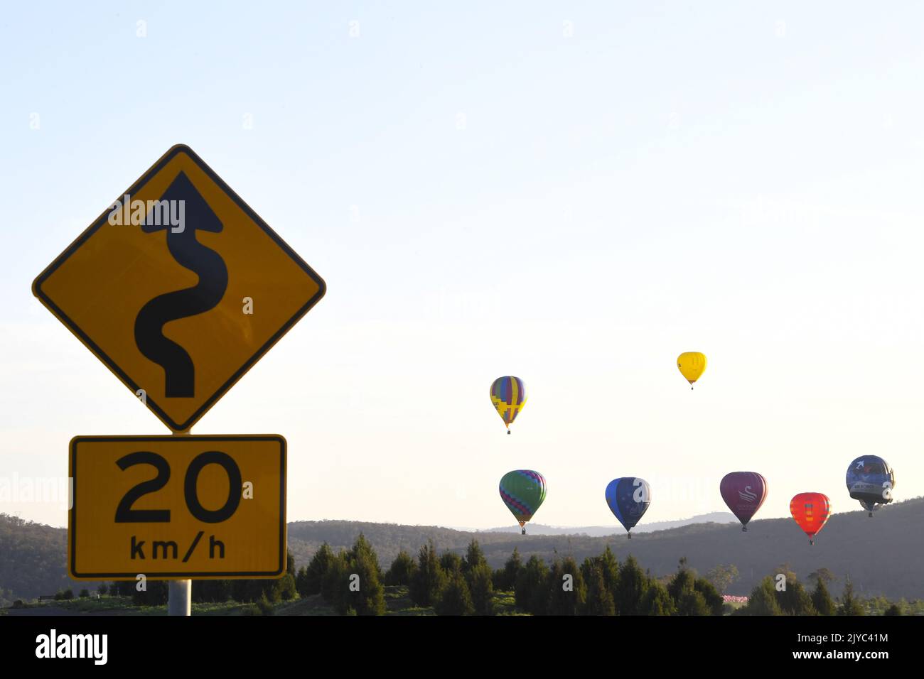 A traffic sign is seen as hot air balloons float over the Arboretum ...