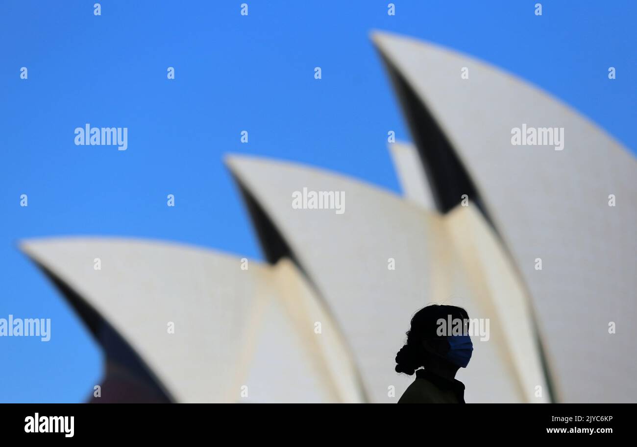 People wear face masks in front of the Sydney Opera House in Sydney ...