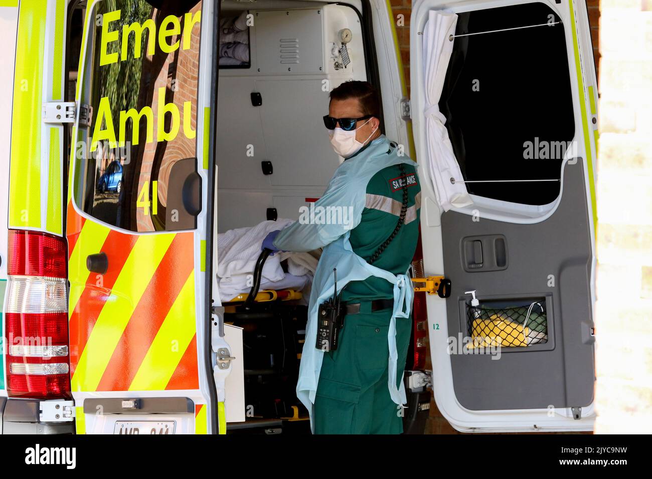A paramedic wears protective clothing while transporting a patient at ...