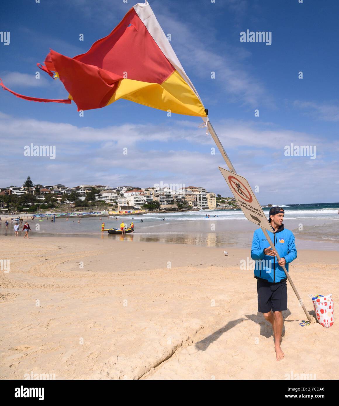 A surf life saver brings down a red and yellow flag as Bondi Beach was ...