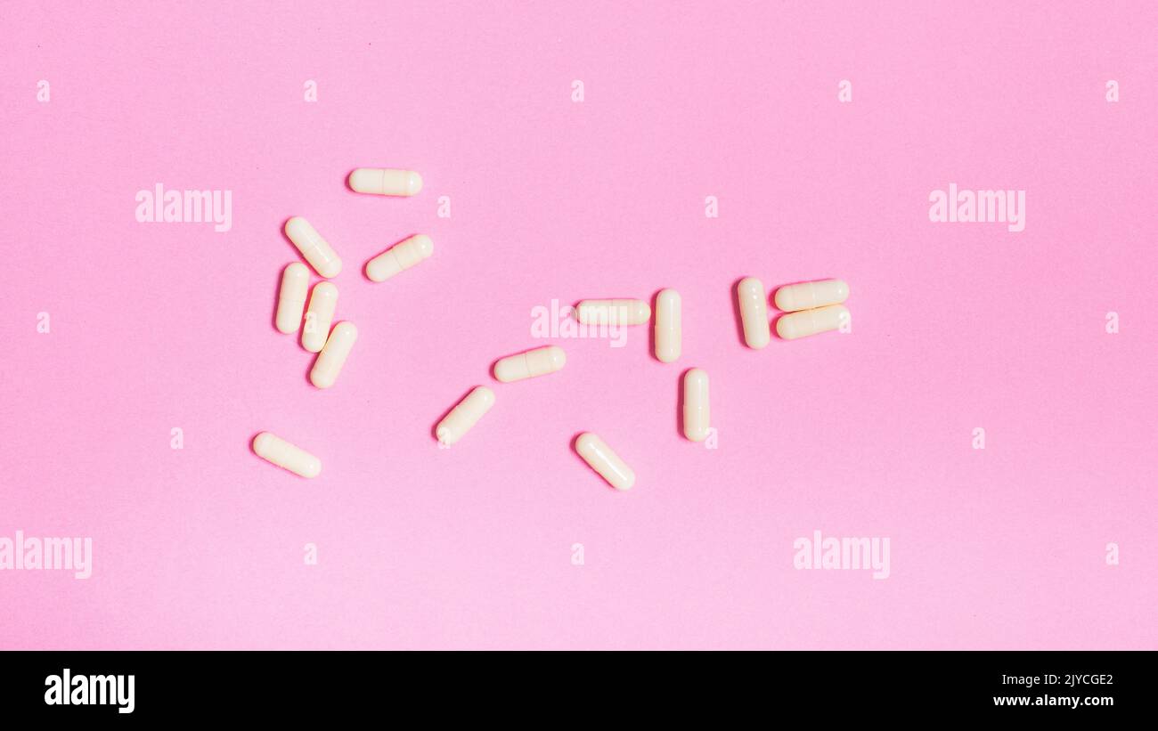 Tablets drugs therapy antibiotic on pastel pink background from above ...