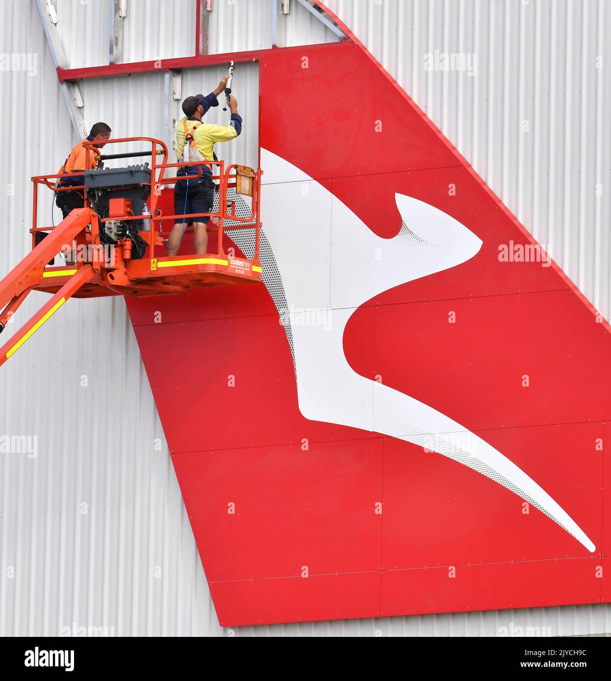 Workmen are seen working on the Qantas flying kangaroo logo on the side ...