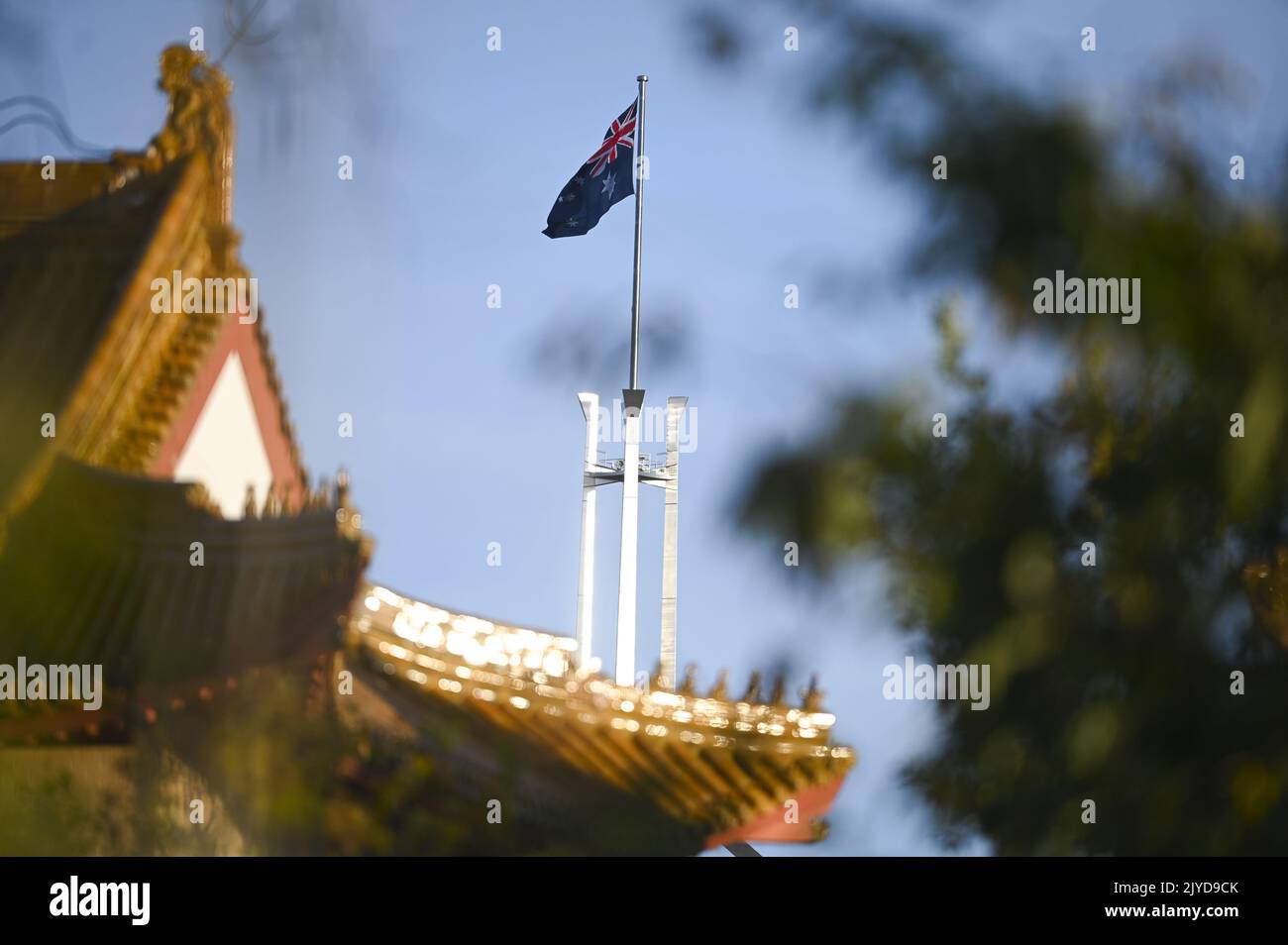 The flag pole of the Australian Parliament is seen behind the roofs of ...