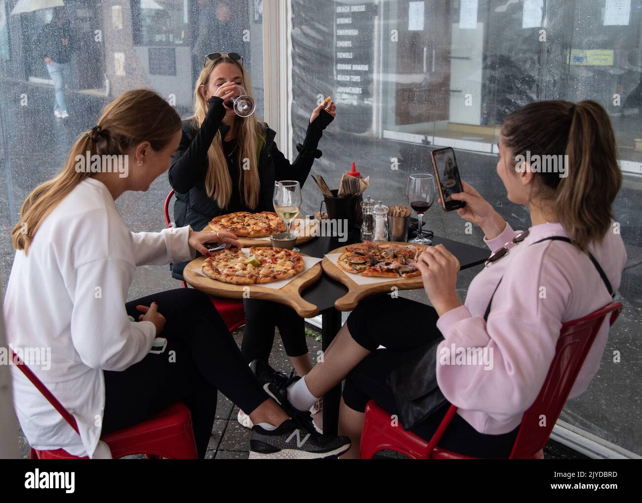 A group of women eating pizza and drinking wine at a restaurant in ...