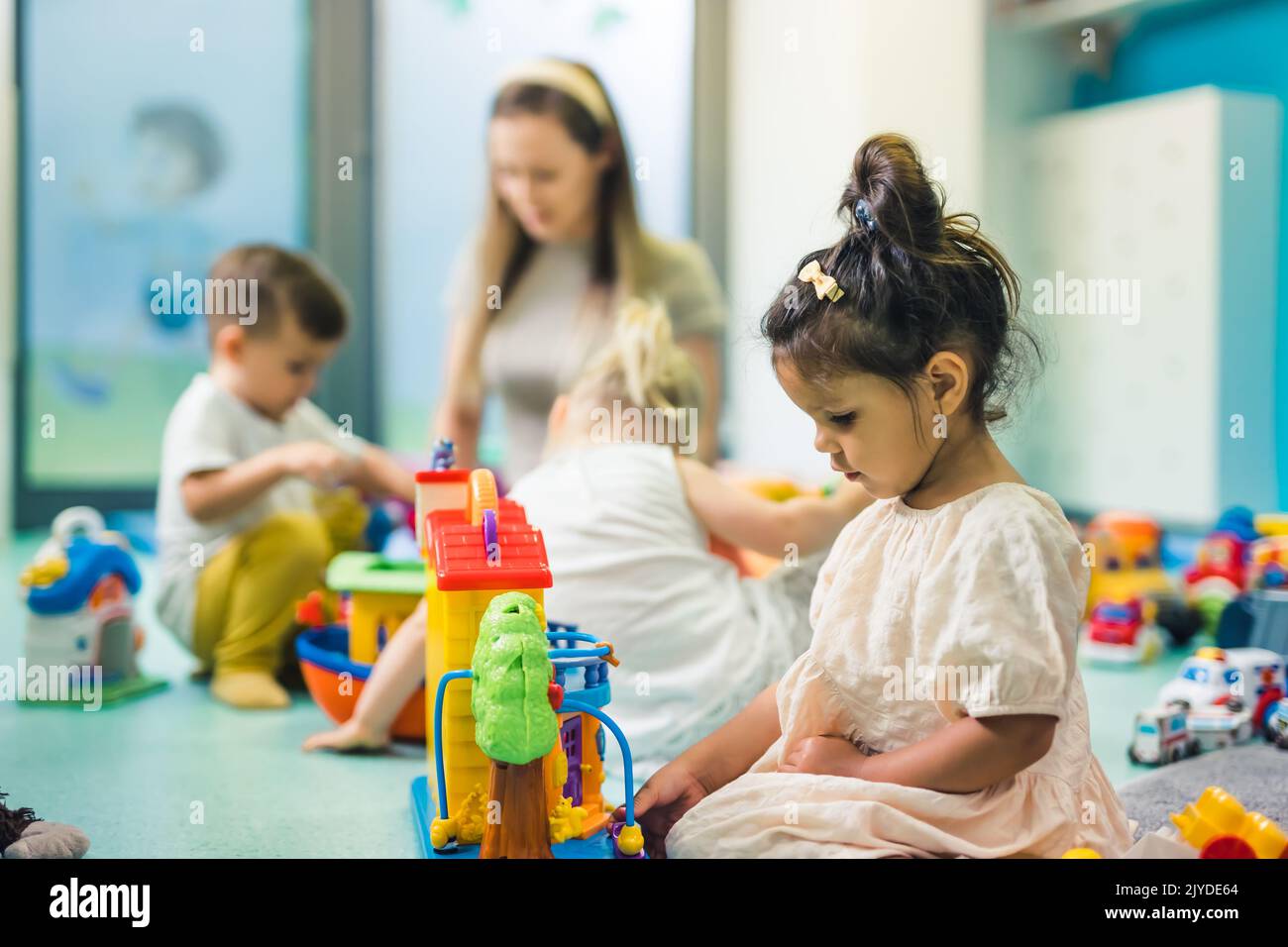 Learning through play at the nursery school. Toddler little girl and the teacher playing with ...