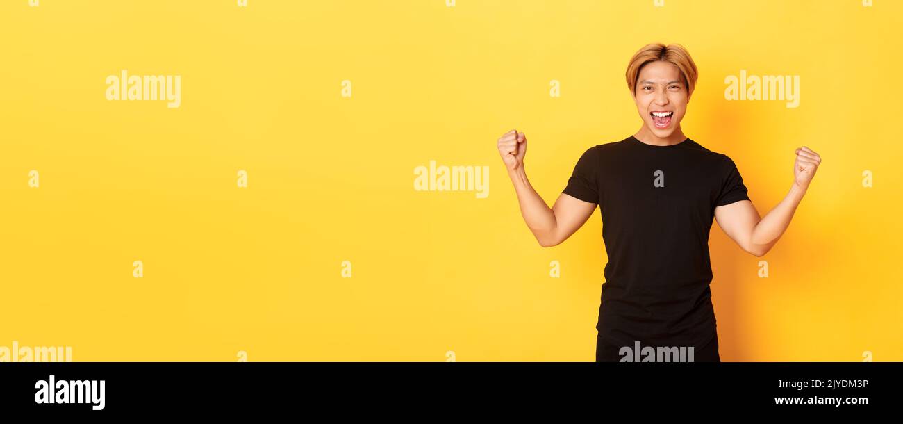Portrait of happy attractive asian man rejoicing, raising hands up and ...
