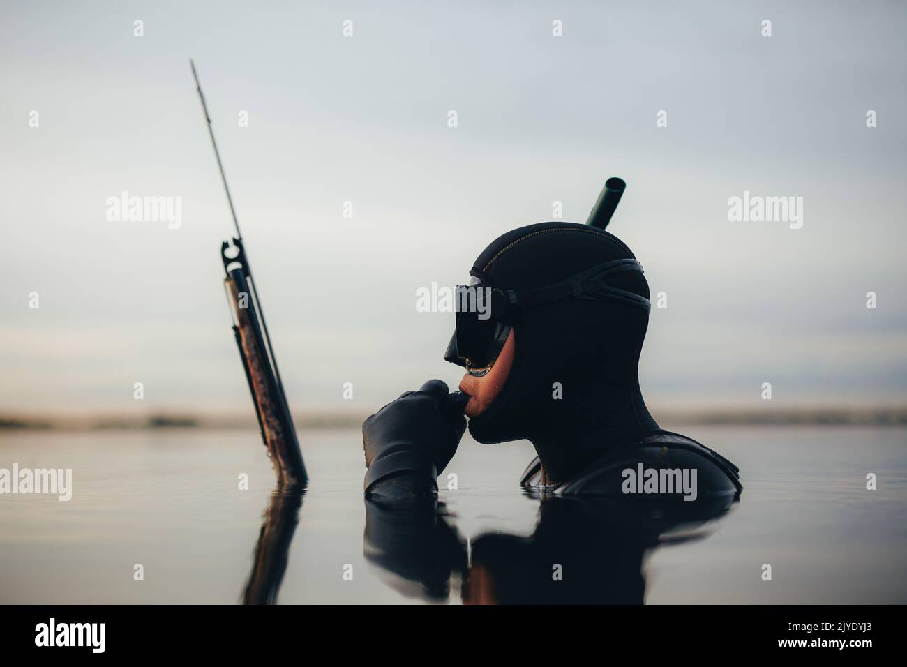 Side view of scuba diver holding a speargun while submerged in sea ...
