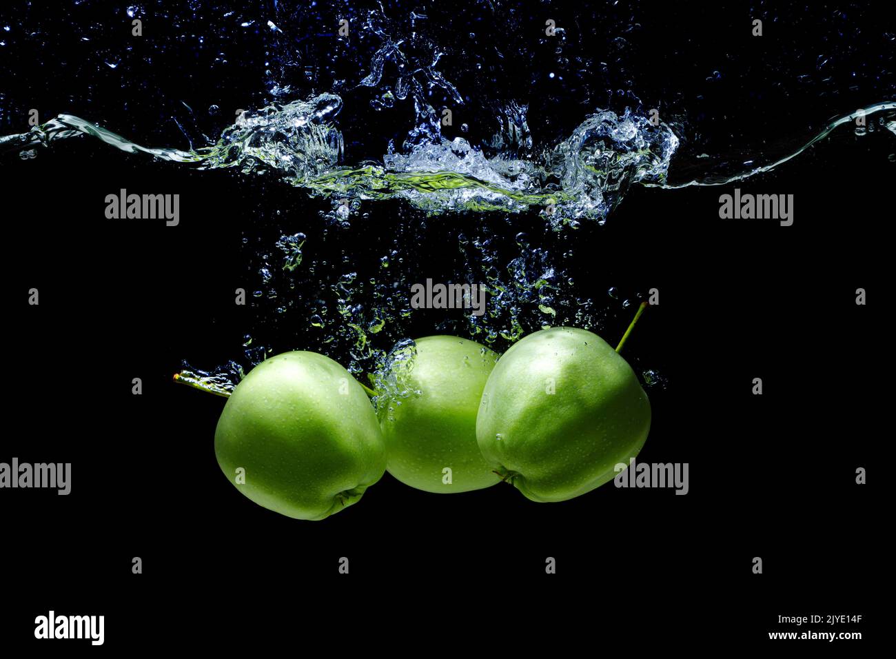 Group of green apples dropped in water with splashes and bubbles ...
