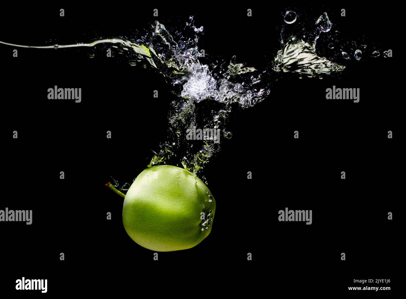 Whole green apple submerges underwater with splashes and bubbles on ...