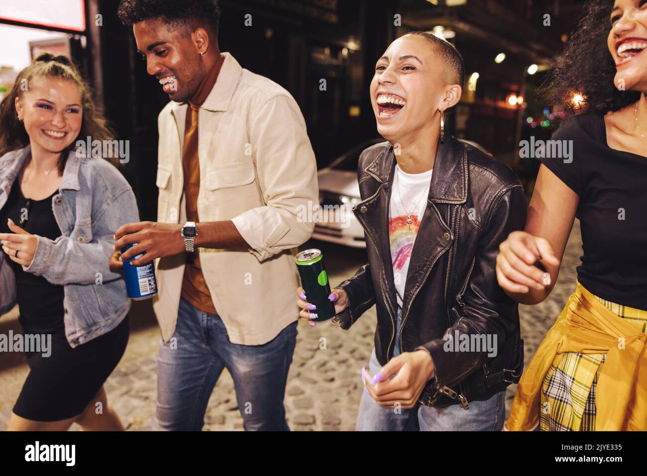 Four friends laughing happily in the city at night. Group of vibrant ...