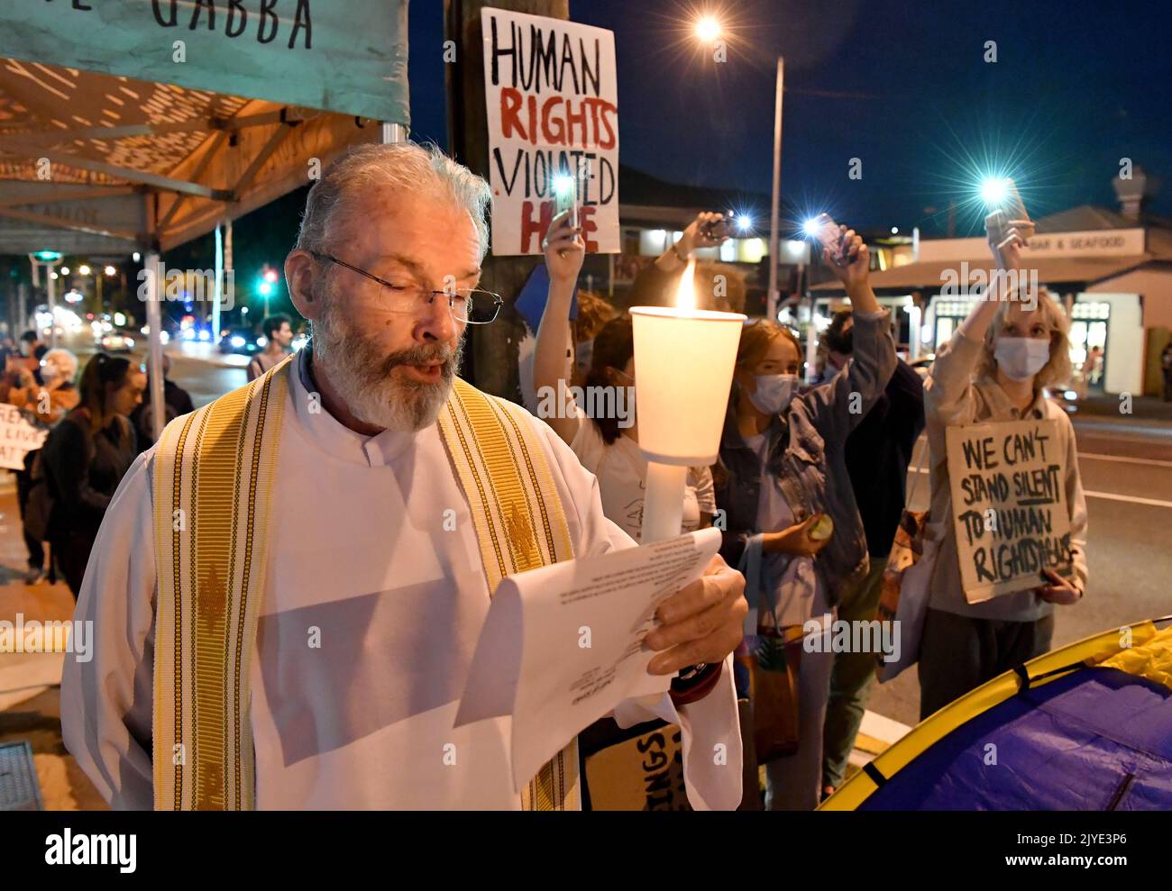 Father Denis Scanlan (left) and protestors are seen outside the ...
