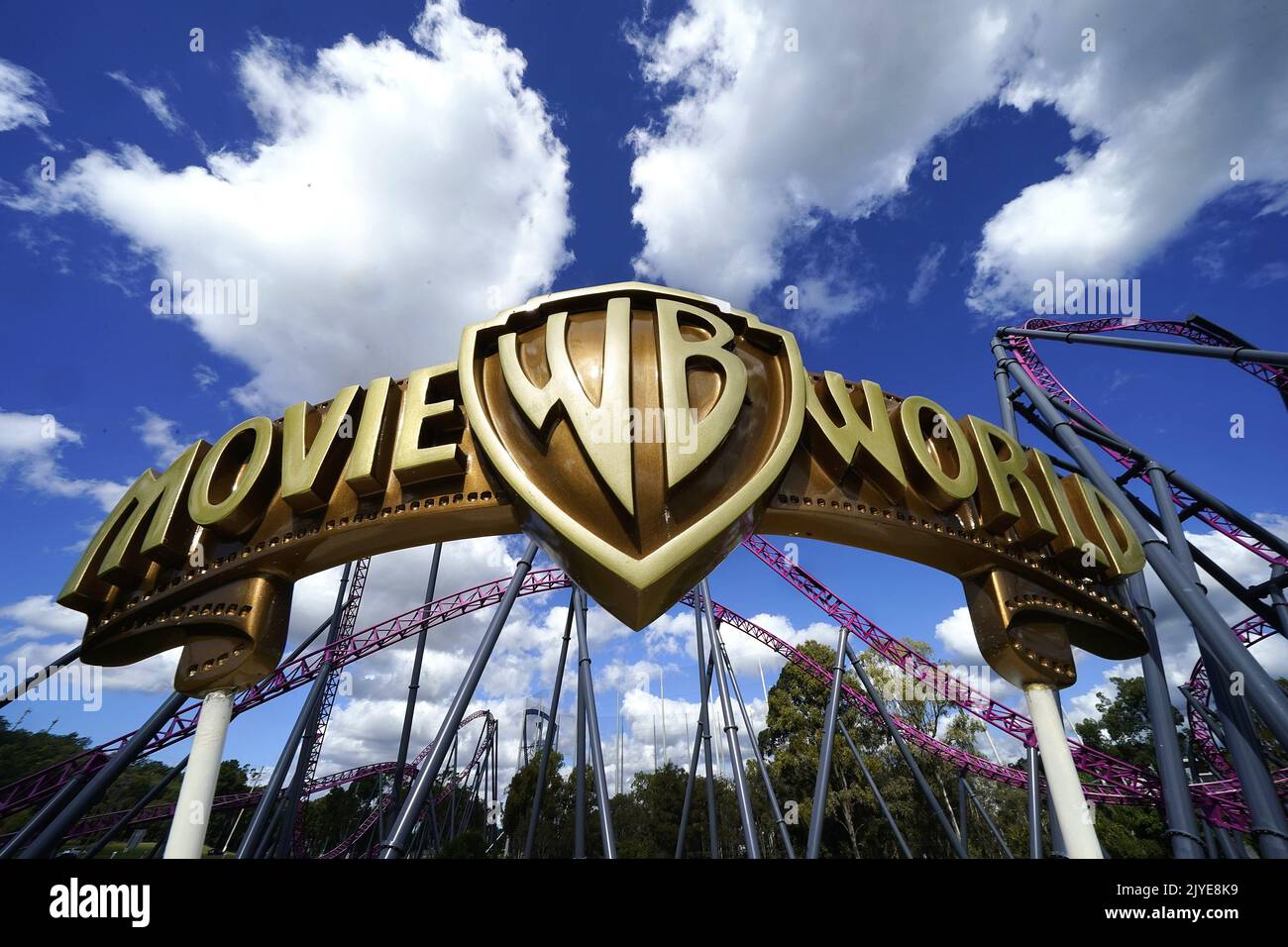 A Warner Brothers Movie World sign is seen in front of a roller-coaster ...
