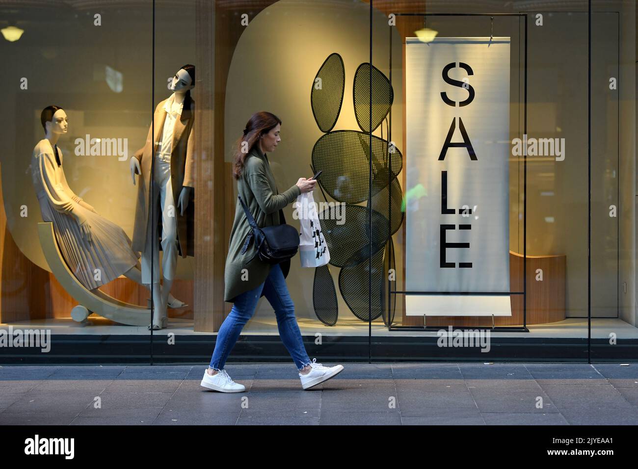 Shoppers walk past retail signage on a shopfront in Sydney, Friday ...
