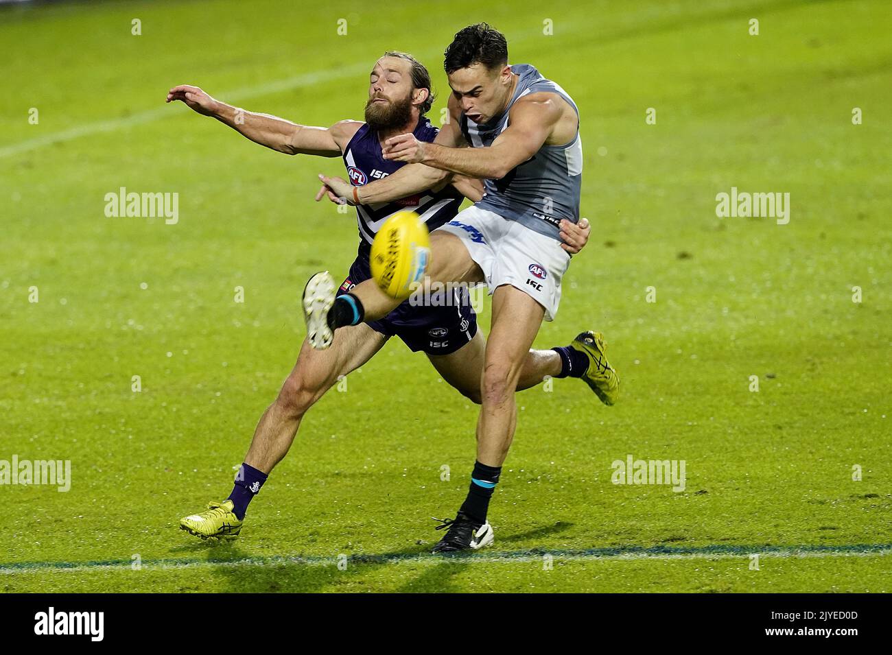 Karl Amon of the Power kicks ahead of Travis Coyler of the Dockers ...