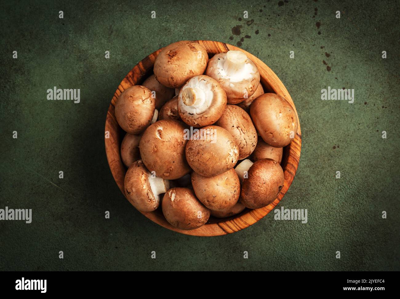 Fresh brown champignon mushrooms in wooden bowl, green stone kitchen ...