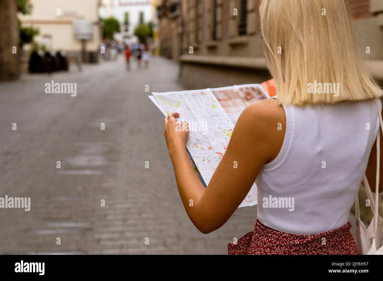 A lost tourist consulting a paper map and looking for her location on ...