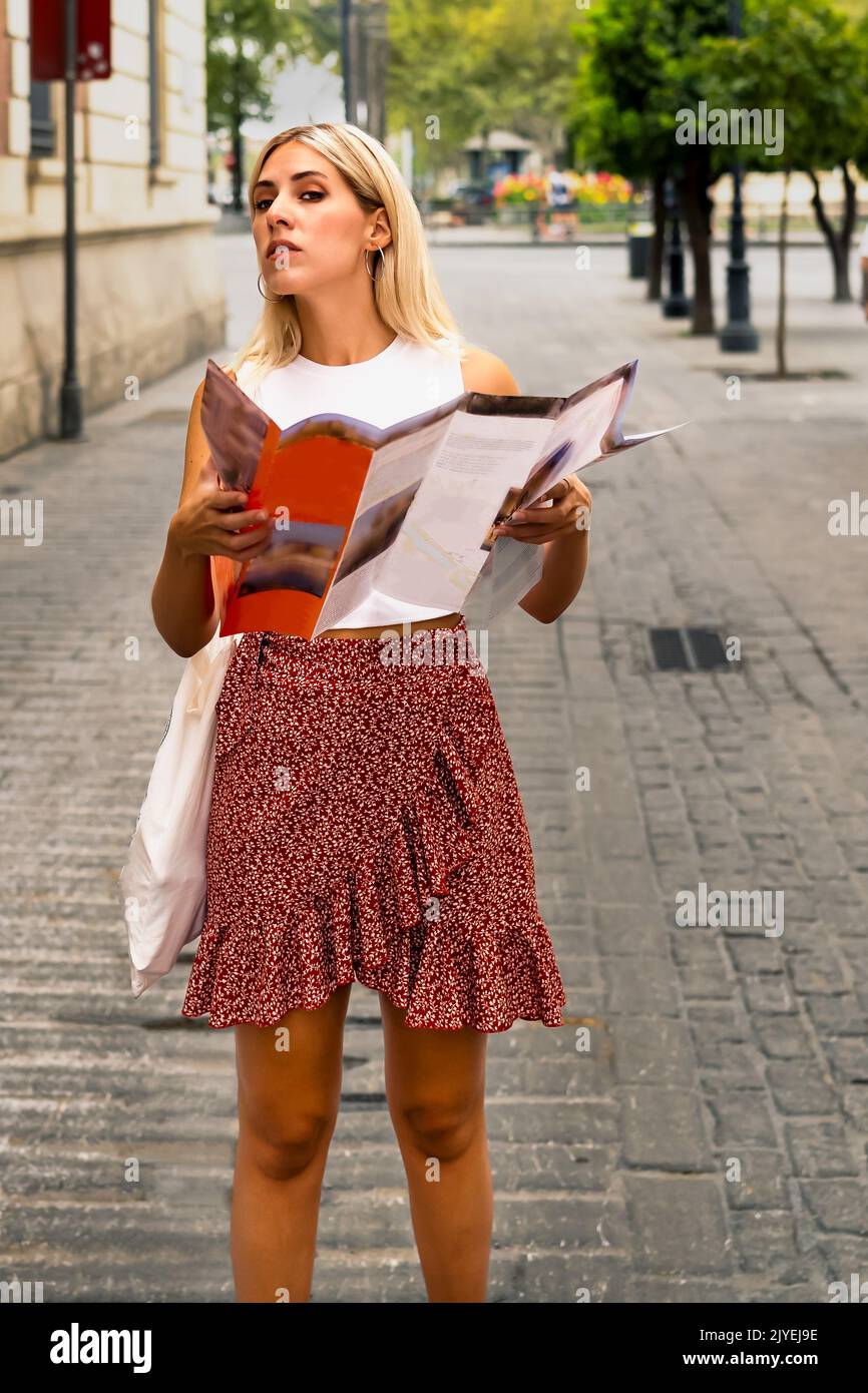 A lost tourist consulting a paper map and looking for her location on ...