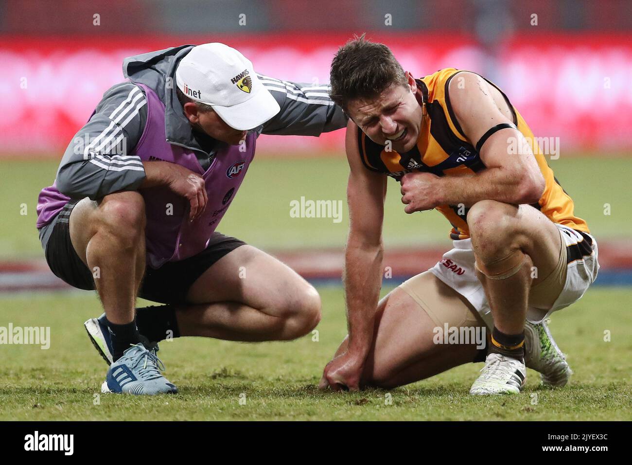 Liam Shiels of the Hawks receives attention from a trainer after a hit ...