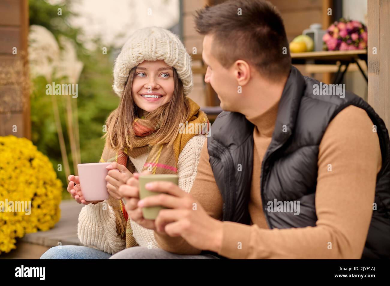 Romantic couple with coffee mugs seated on the veranda Stock Photo - Alamy
