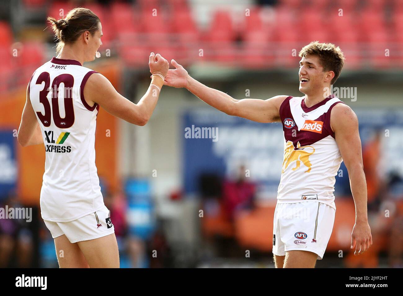 Zac Bailey of the Lions celebrates kicking a goal with team mate Eric ...