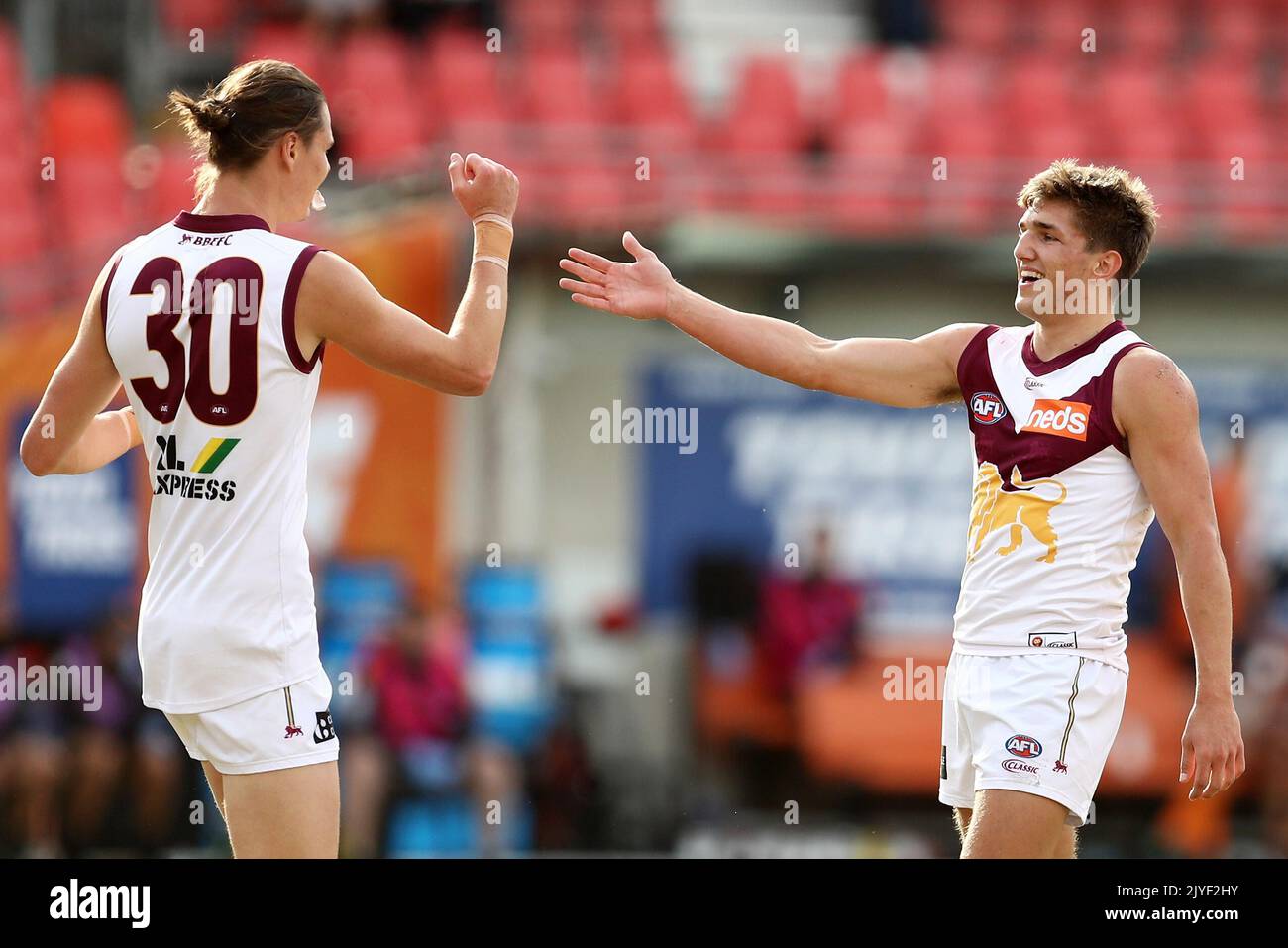 Zac Bailey of the Lions celebrates kicking a goal with team mate Eric ...
