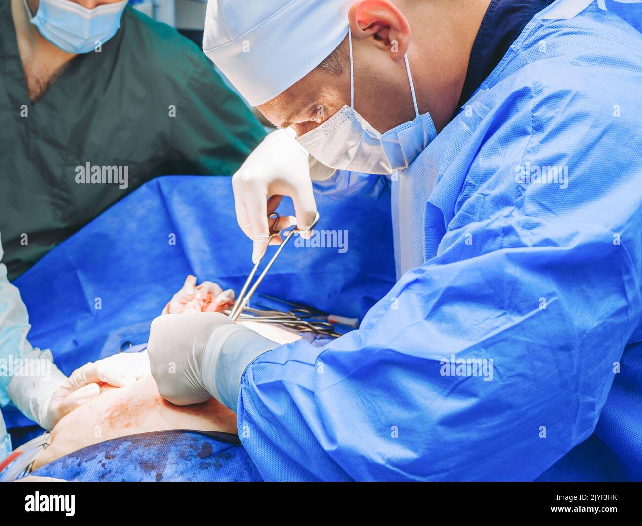A male surgeon close-up operates on a patient with surgical instruments ...