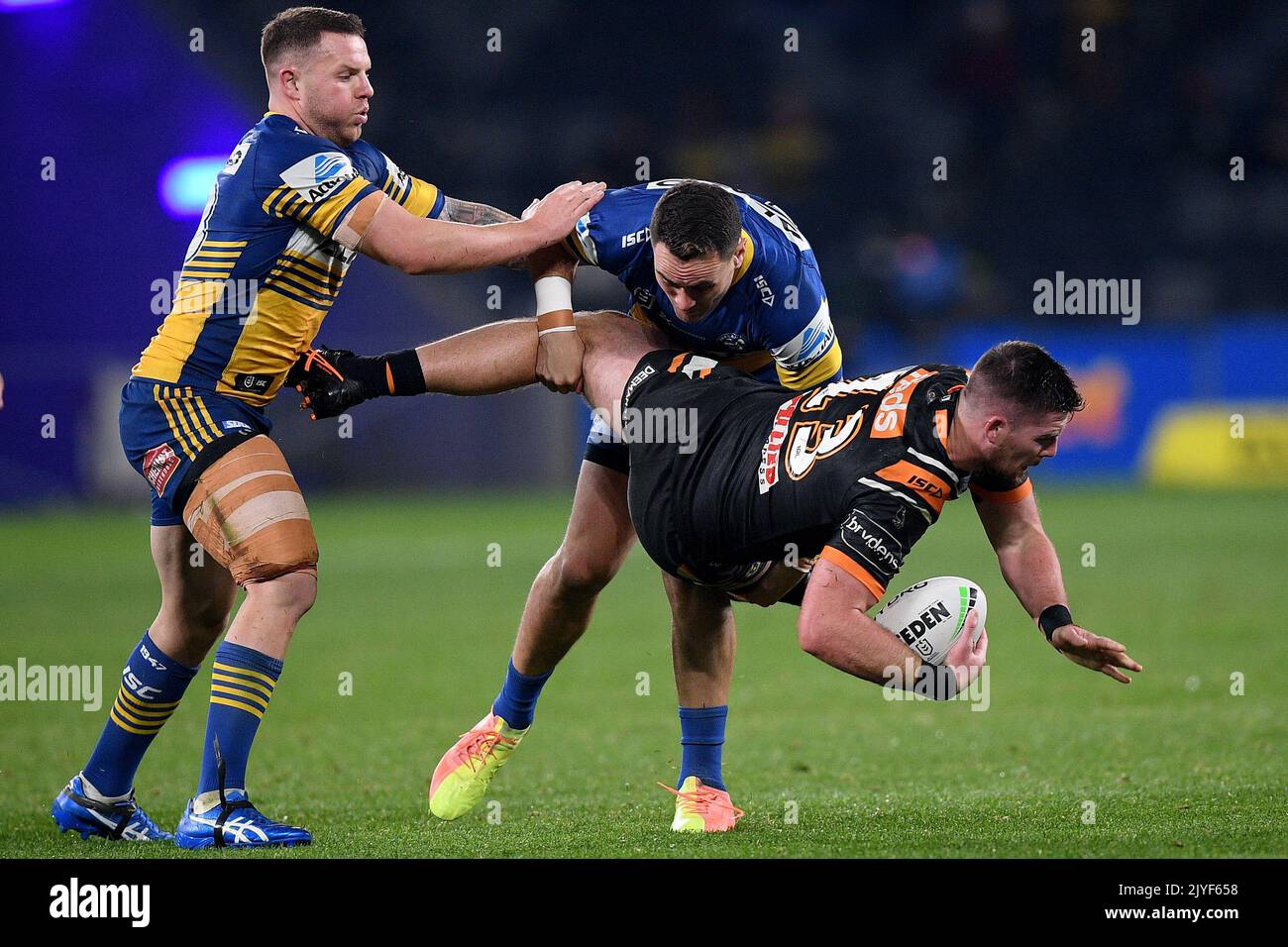 Matt Eisenhuth of the Tigers is tackled by Brad Takairangi of the Eels ...