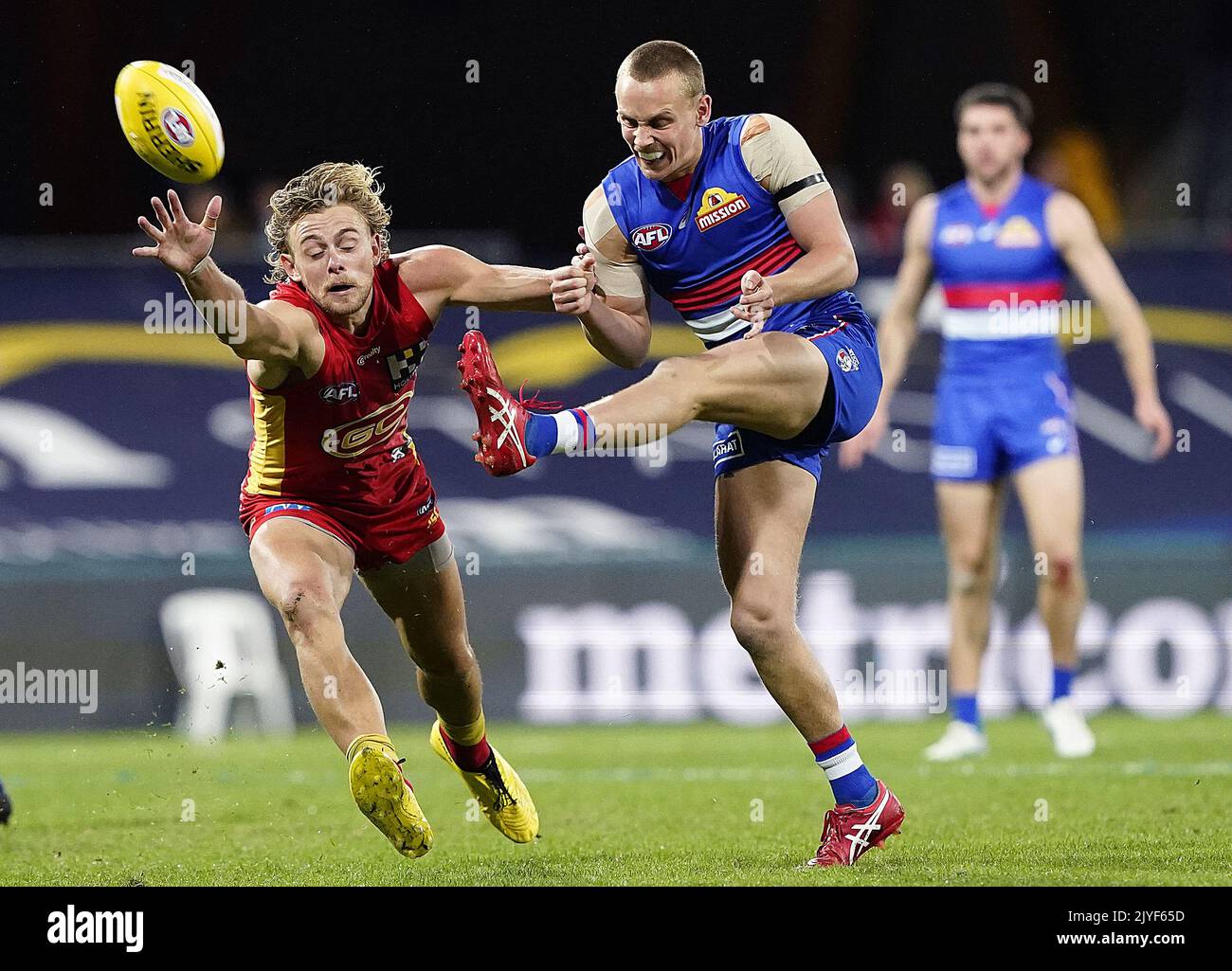 Callum Porter of the Bulldogs kicks ahead of Hugh Greenwood of the Suns ...